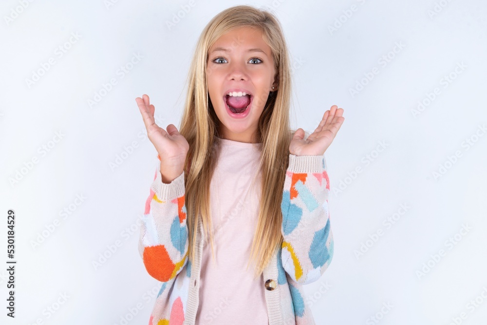 Surprised happy little kid girl wearing colorful yarn jacket over white ...
