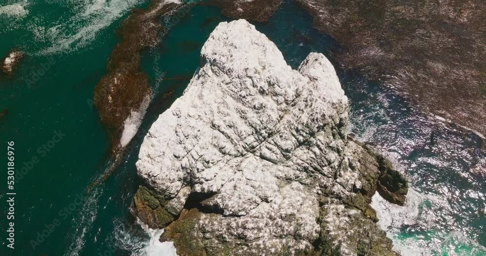 White rock peeping out from blue water of ocean on sunny day. Waves ...