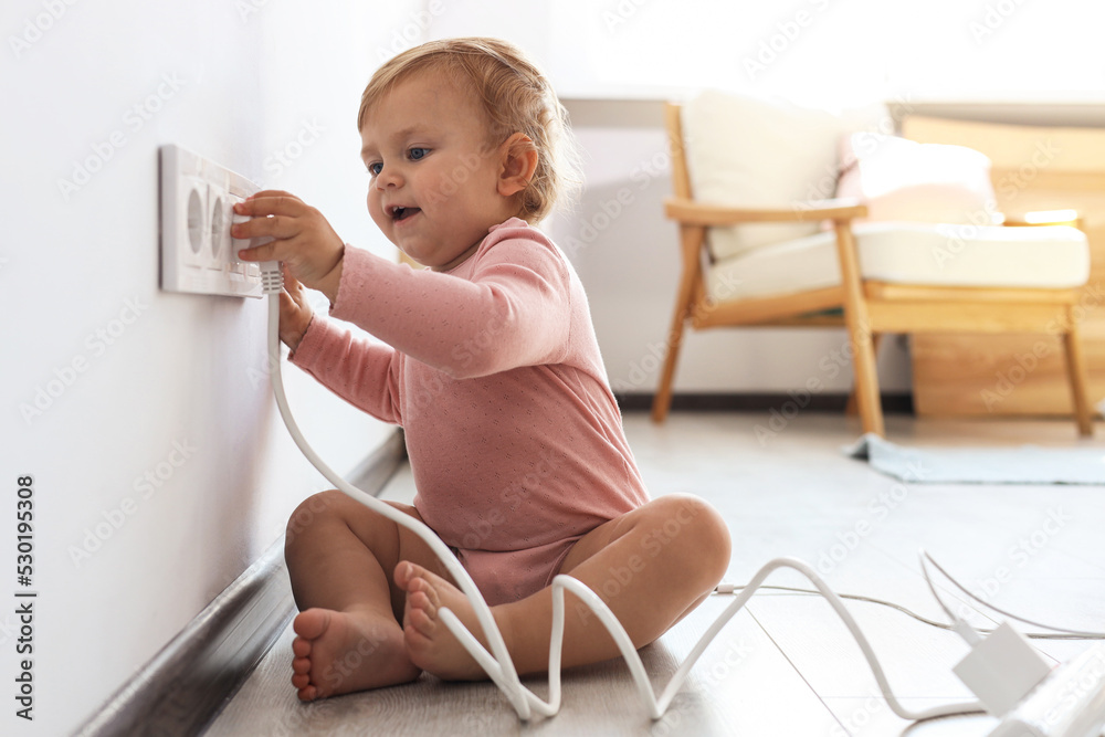 Cute baby playing with electrical socket and plug at home. Dangerous ...