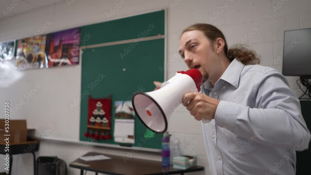 Vidéo Stock Angry teacher shouting in classroom into megaphone ...