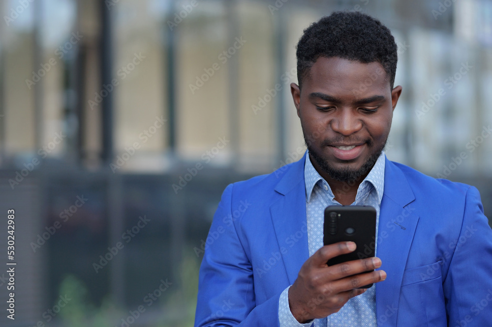 African American man types messages to workers on black smartphone ...