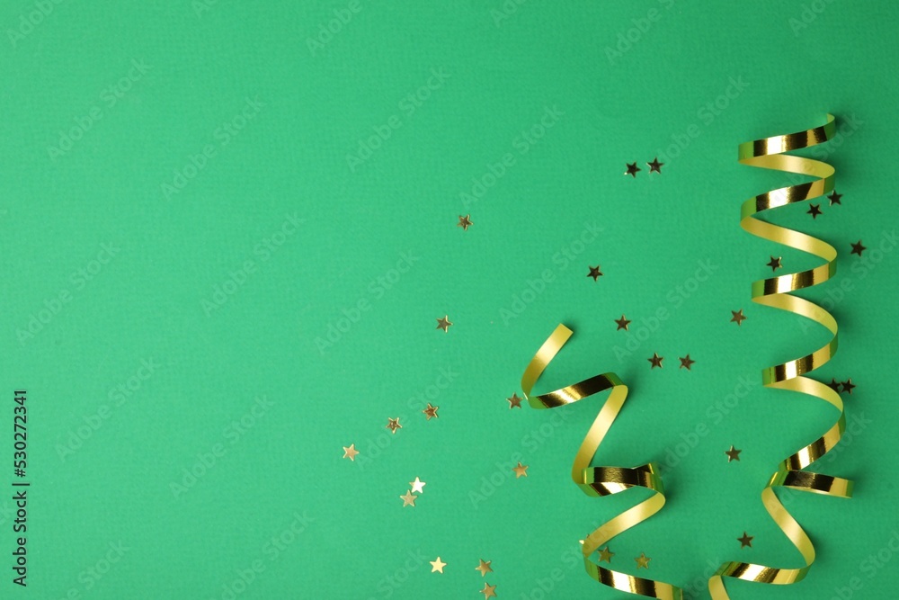 Shiny golden serpentine streamers and confetti on green background ...