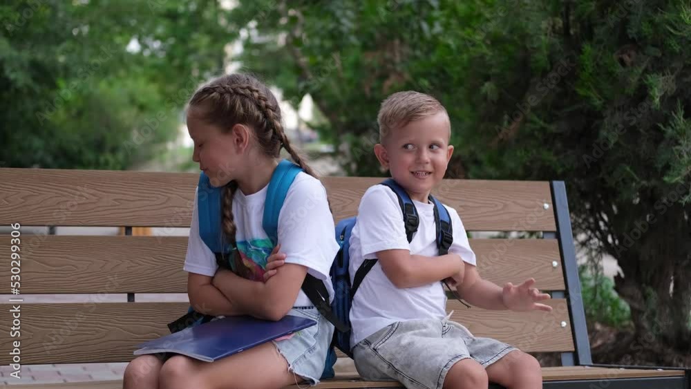 Brother and sister sit offended on benches and hit each other. Childish ...