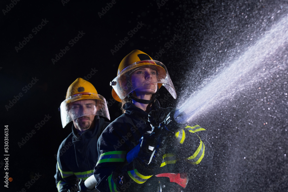 Firefighters using a water hose to eliminate a fire hazard. Team of ...