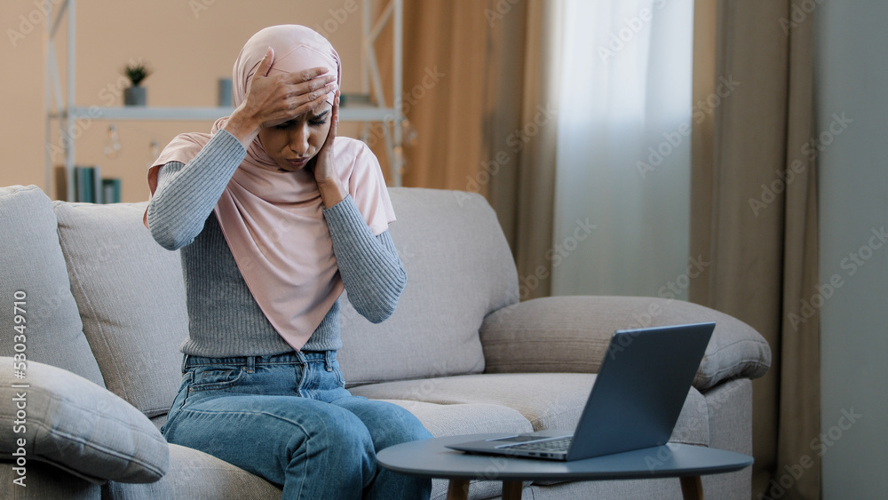Muslim islamic arabian woman in pink hijab sitting on sofa working ...
