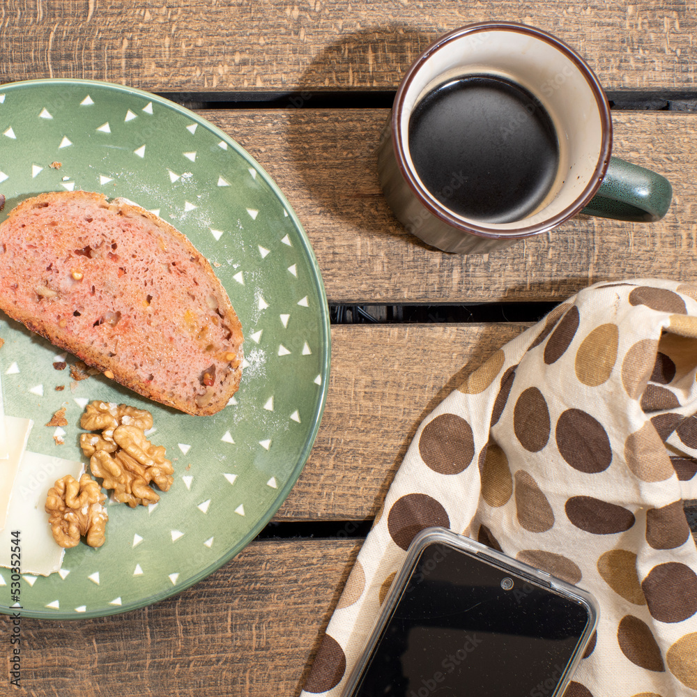 Tostada con pan con tomate, nueces y trozo de queso, desayuno con movil ...
