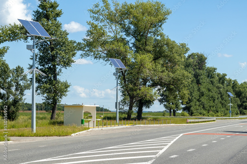 Lamp post with solar panel system on road with blue sky and trees ...