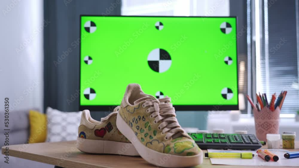 shoes design, a monitor with a green screen stands on a table with ...