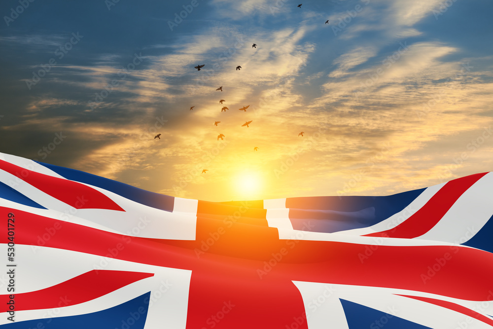 National flags of United Kingdom with flying birds on sunset sky ...