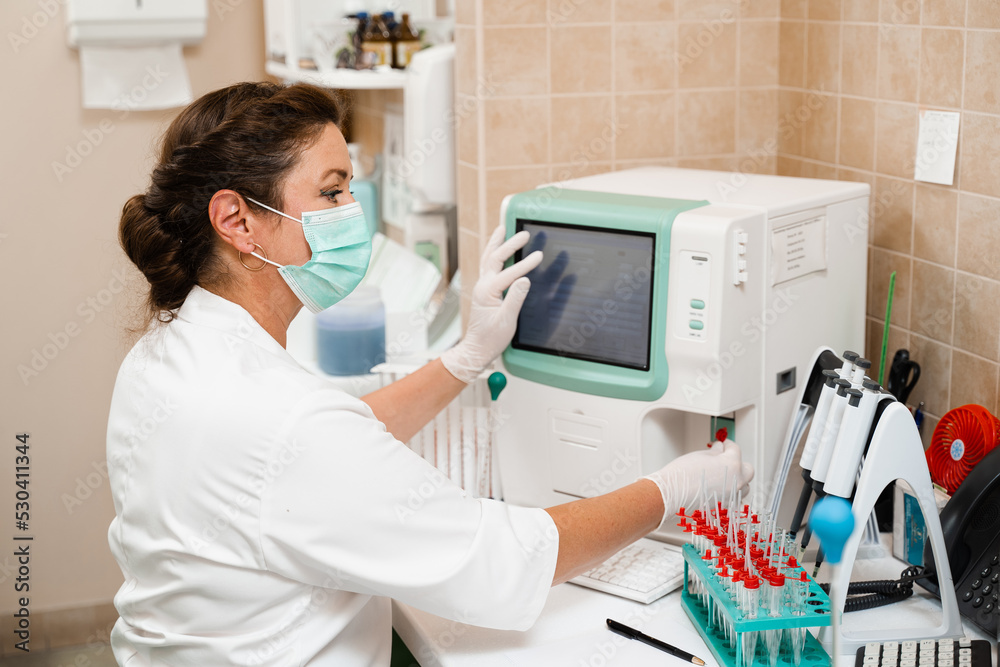 Laboratory assistant works on blood analyzer and makes hematological ...