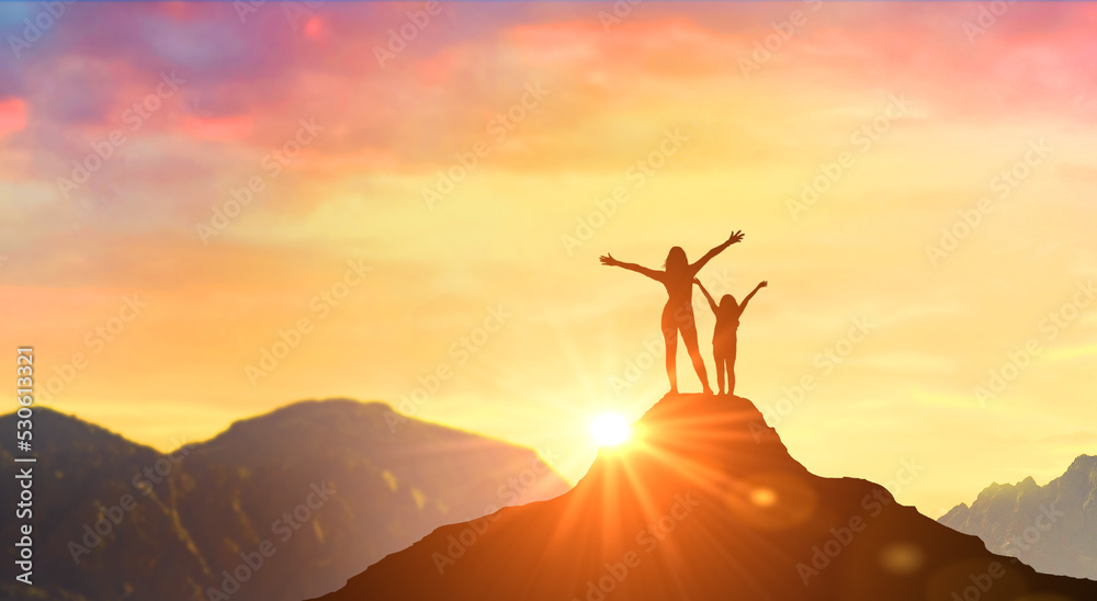 Mother and daughter meet dawn at peak in mountains. Woman on mountain ...