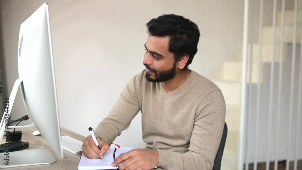 Concentrated positive Indian man thinking, taking notes while sitting ...