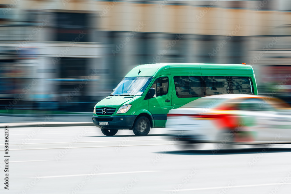 Green Mercedes-Benz Sprinter minibus van moving on city speedway road ...
