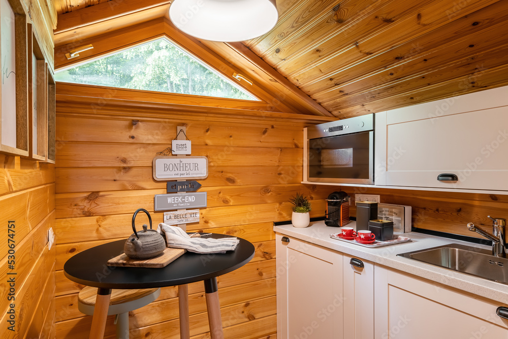 Compact kitchen with small round dining table in wooden house. Village ...