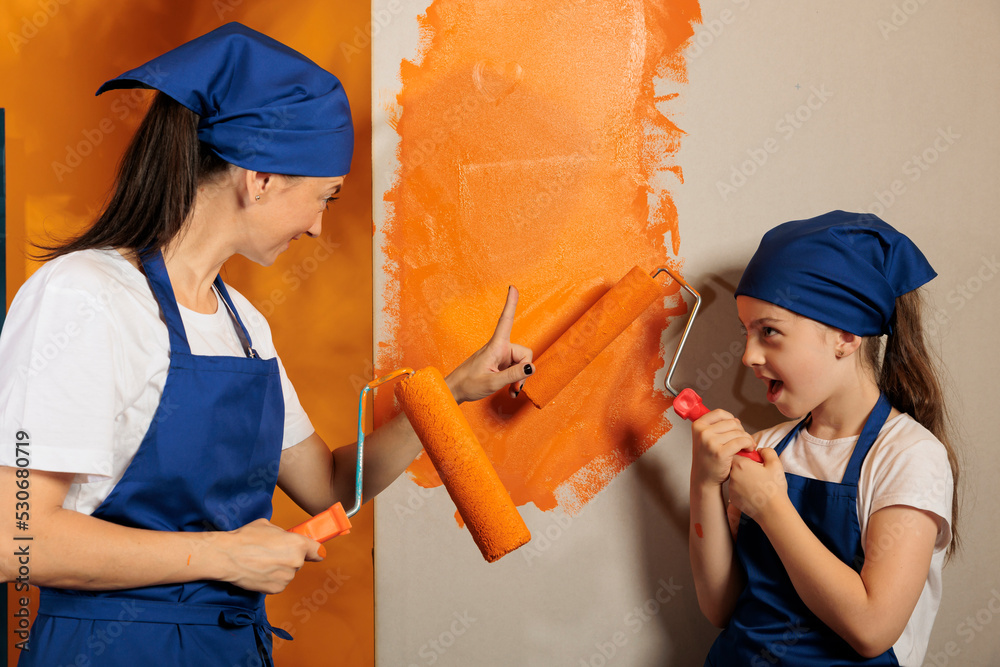 Young people having fun painting at home, using orange paint color on ...