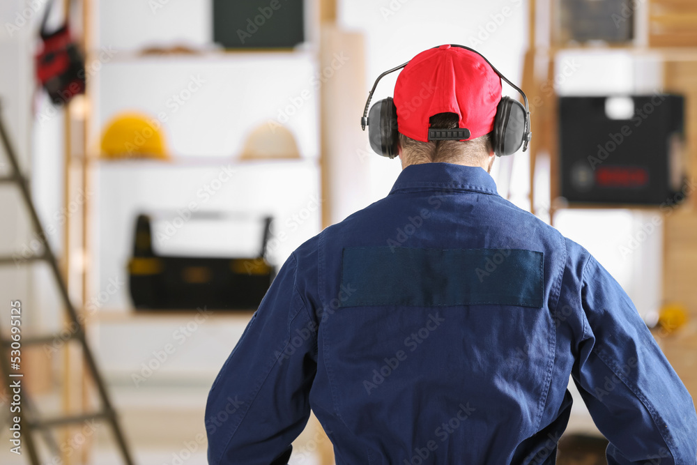 Worker wearing safety headphones indoors, back view. Hearing protection ...