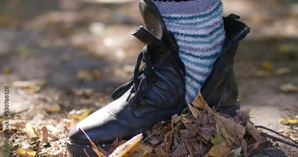 Side view black leather boot with hands of homeless woman tying ...
