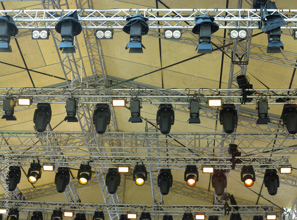 Spotlight devices in a row on rigging steel trusses, installation of ...