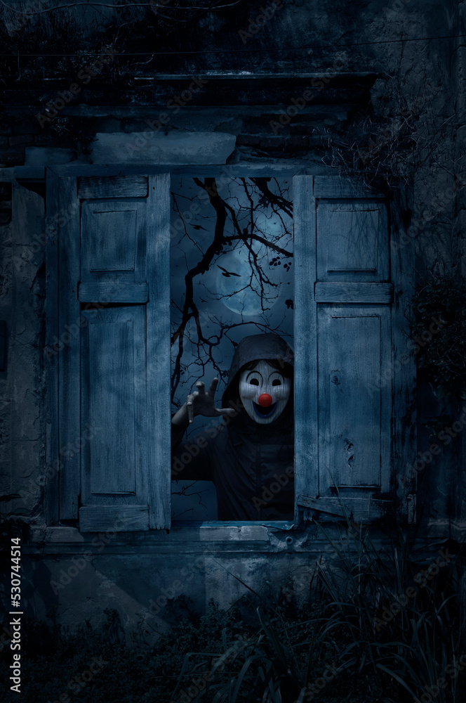 Scary evil clown wear jacket standing in old damaged wood window with ...