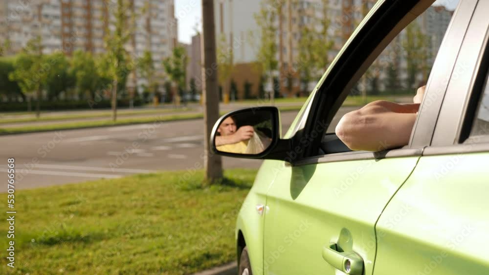 A young man throws a plastic bag with garbage out of a car window in a ...
