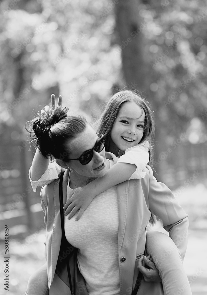 Cute young daughter on a piggy back ride with her mother.Happy family ...