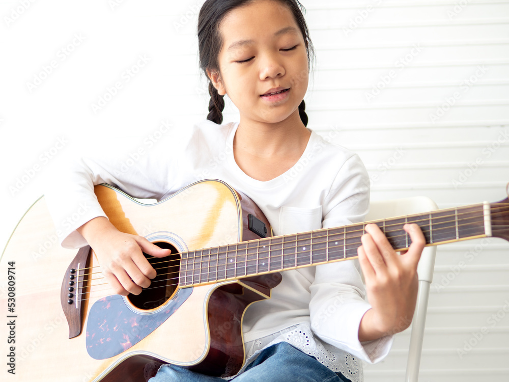 Talented child musician and acoustic guitar sit on couch white ...