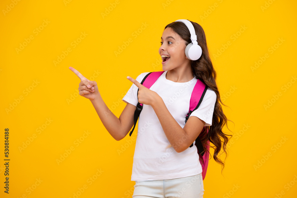 Amazed teen girl. School girl in headphones on isolated studio ...