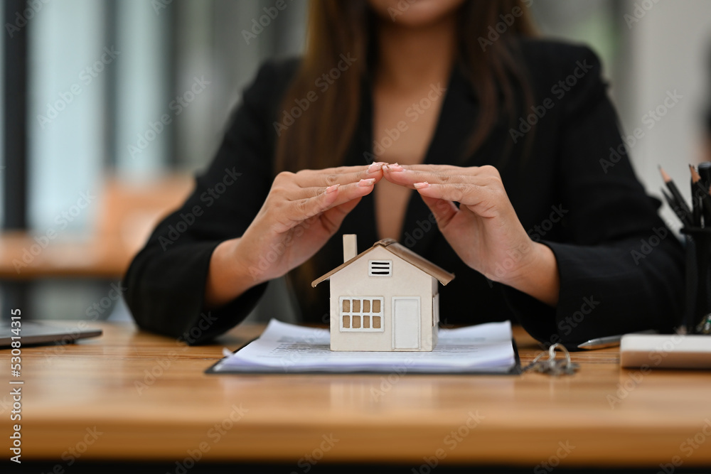 Protect your house concept. Small model of house covered by hands ...