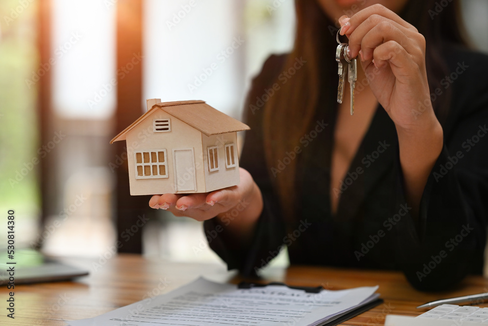 Cropped image of real estate agent presenting Model of house and key on ...