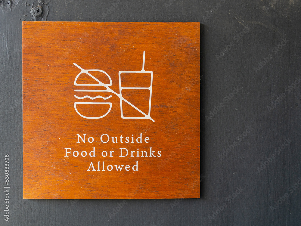 A light brown sign over a dark grey background banning people to bring ...