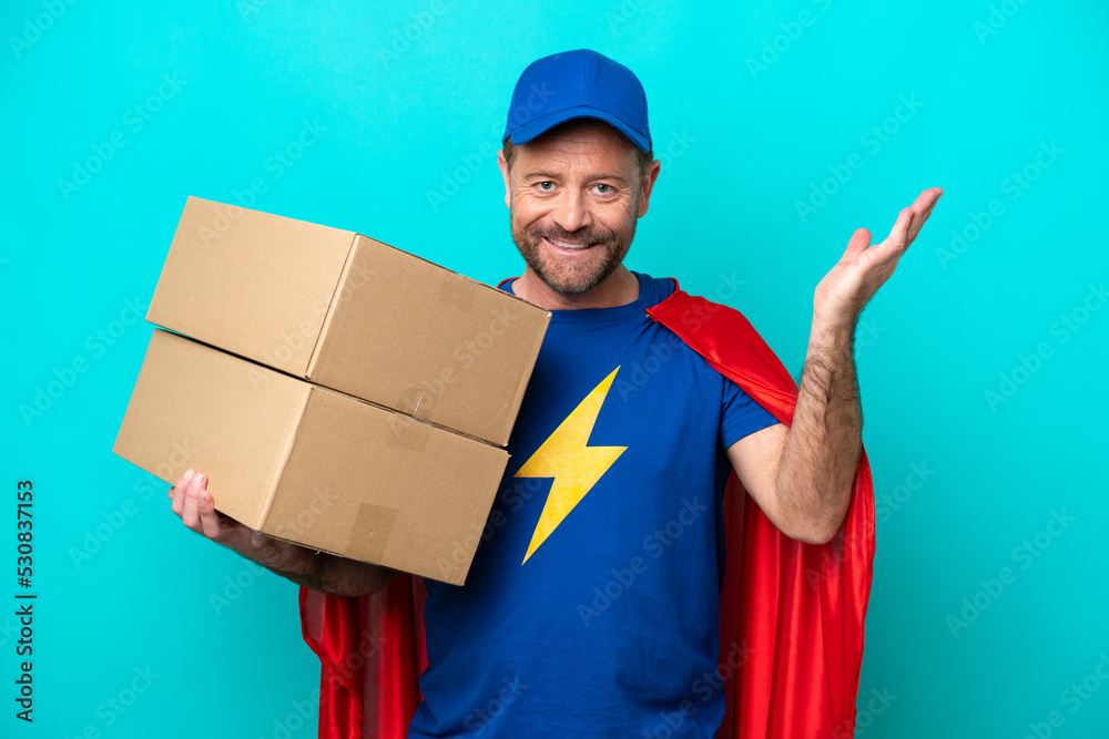 Super Hero delivery man isolated on blue background extending hands to ...