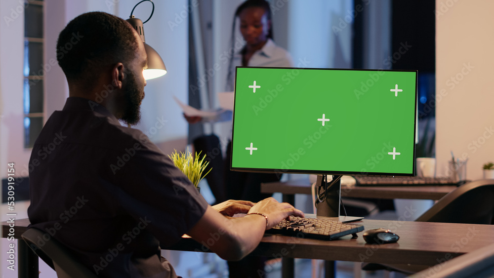 Office employee working with greenscreen display on computer late at ...