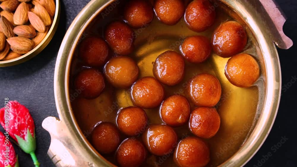 Woman hand pouring sugar syrup Gulab jamun , gulaab jamun golden bowl ...