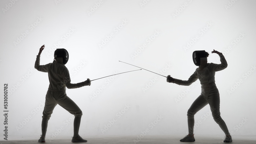 Side view of two young female swordswoman with crossed rapiers ...
