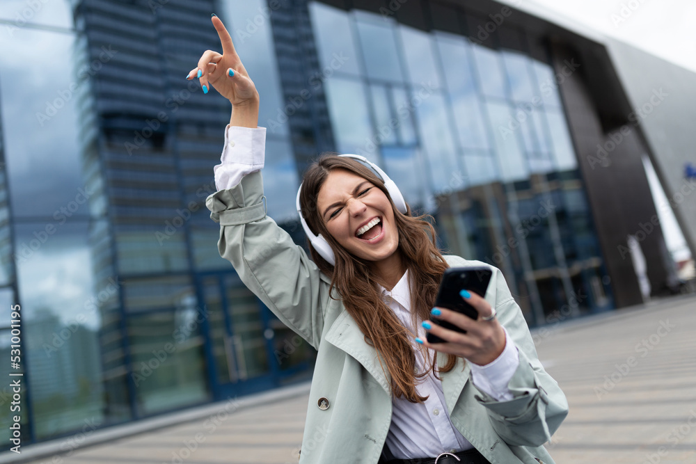 satisfied ambitious young woman dancing with a mobile phone in her ...