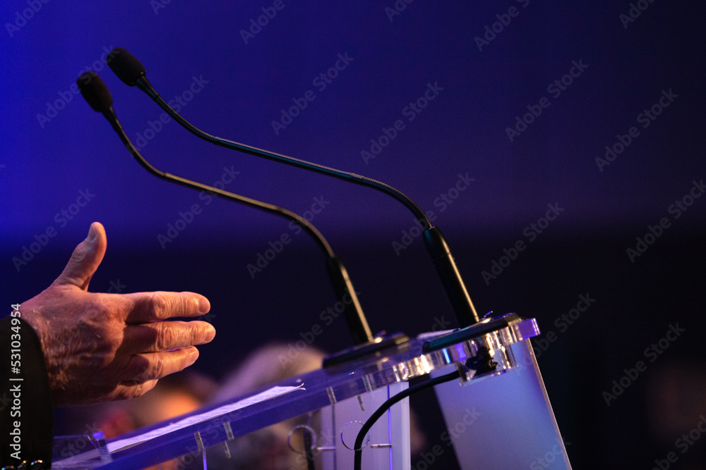 focus sur un micro et les mains d'un orateur prononçant un discours à ...