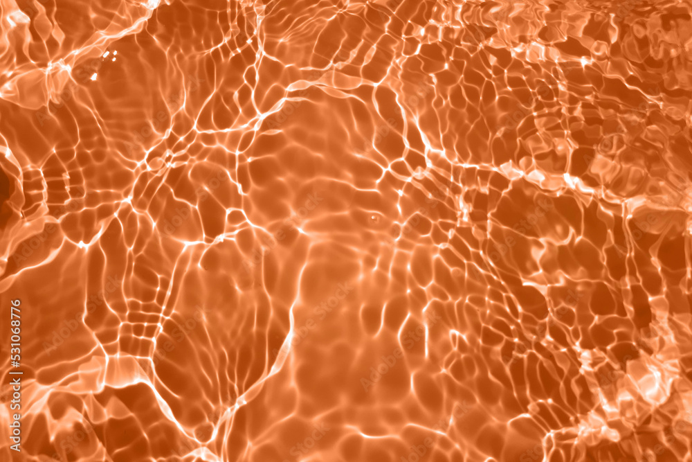 Defocus blurred transparent orange colored clear calm water surface ...