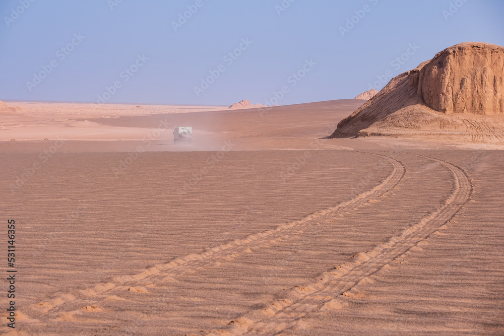 Footprints in the desert with the camper truck behind a cloud of dust ...
