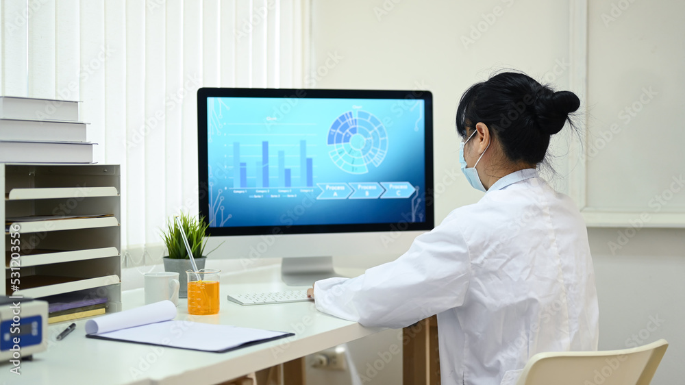 Back view of female scientist working on personal computer with screen ...