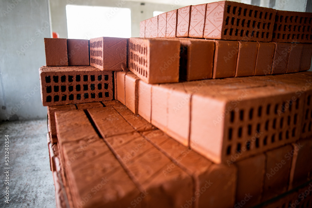 Red clay bricks are stacked on wooden pallets. Production of bricks ...