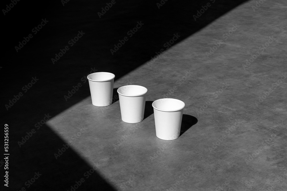 A row of blank coffee paper cups mockup, front view, on concrete ...