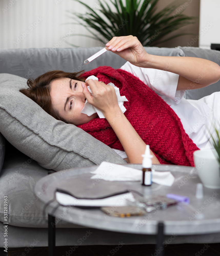 Young sick woman has a cold and high fever while checking body ...