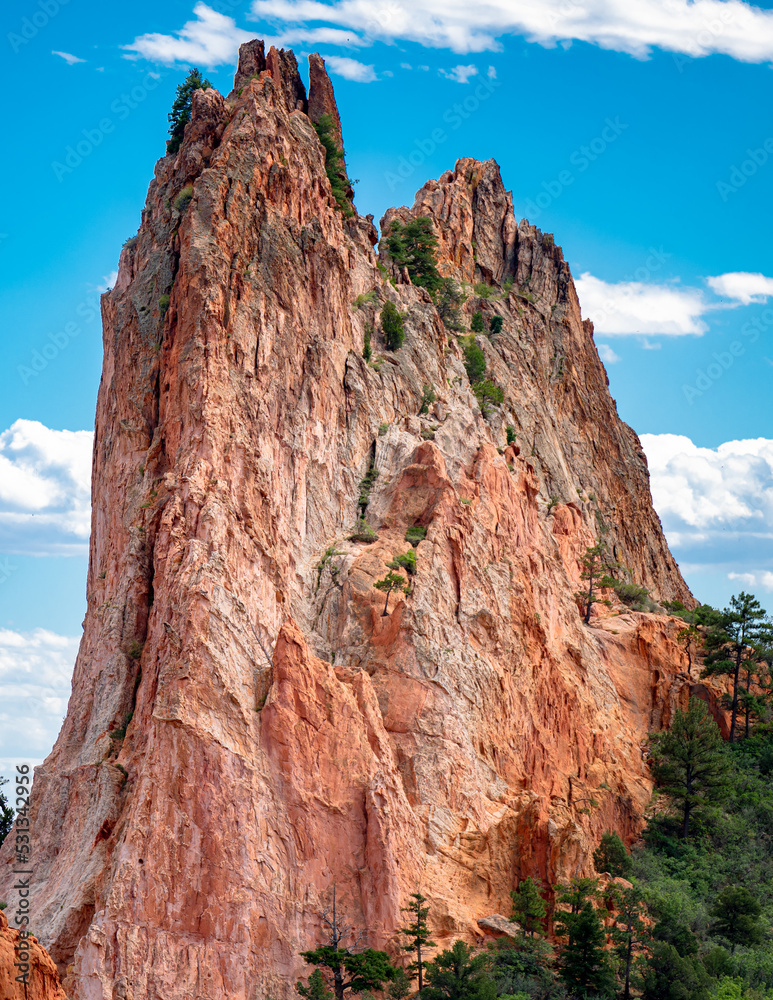 Massive red, beige, grey, rock monolith surrounded by scrub oak, pine ...
