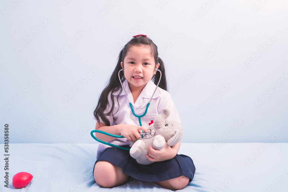 cute girls in medical uniform and stethoscope playing with a doll to be ...