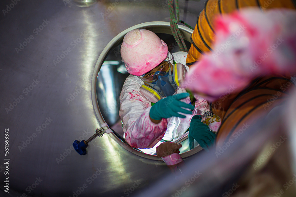 Top view male climbs up the stairs into the tank stainless chemical ...