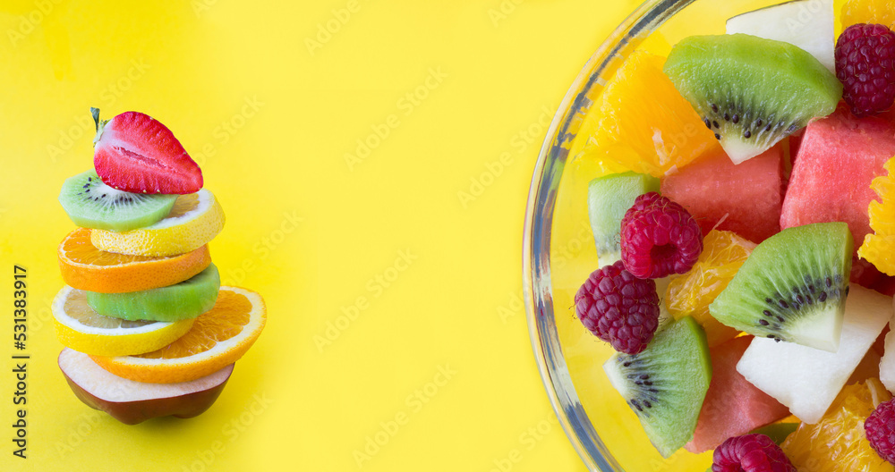 Pyramid of chopped fruit in balance and fruit salad on the yellow ...