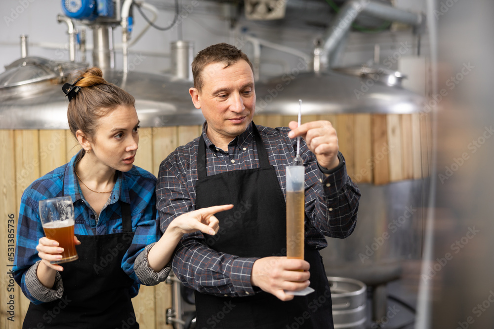 Foto de Man brewmaster measuring beer sample with alcoholometer. His ...