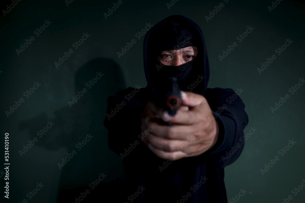 Foto de Criminal man in black hood holding a gun pointing victim, mask ...
