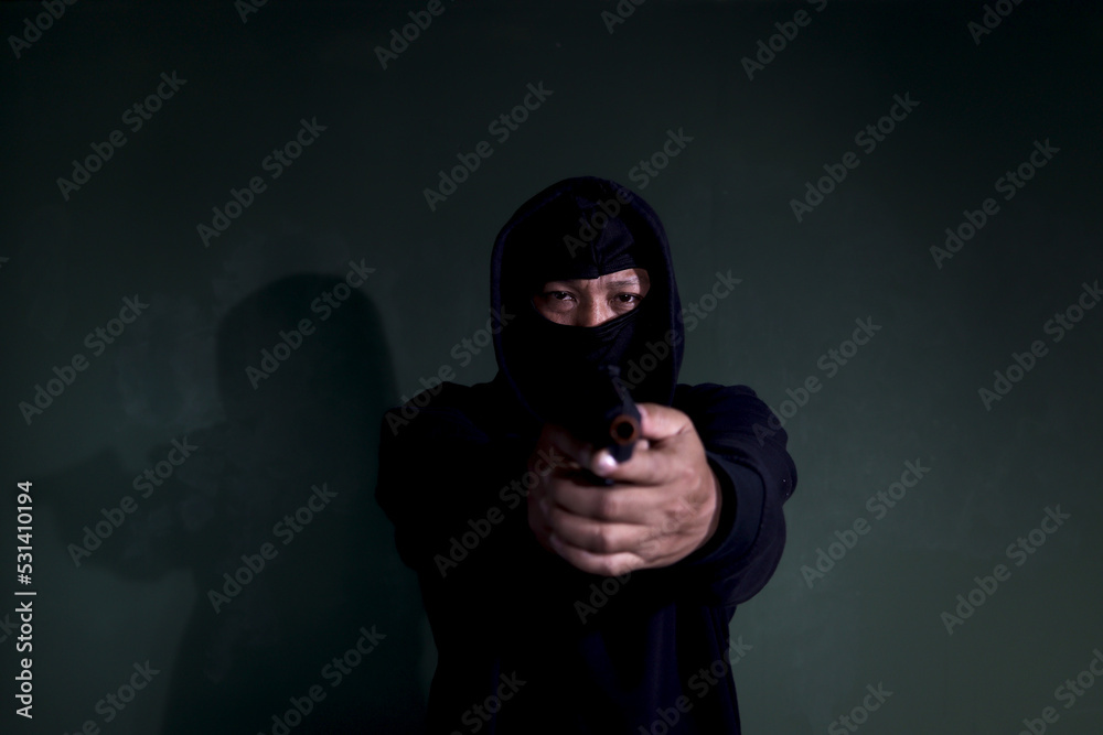 Criminal man in black hood holding a gun pointing victim, mask thief ...