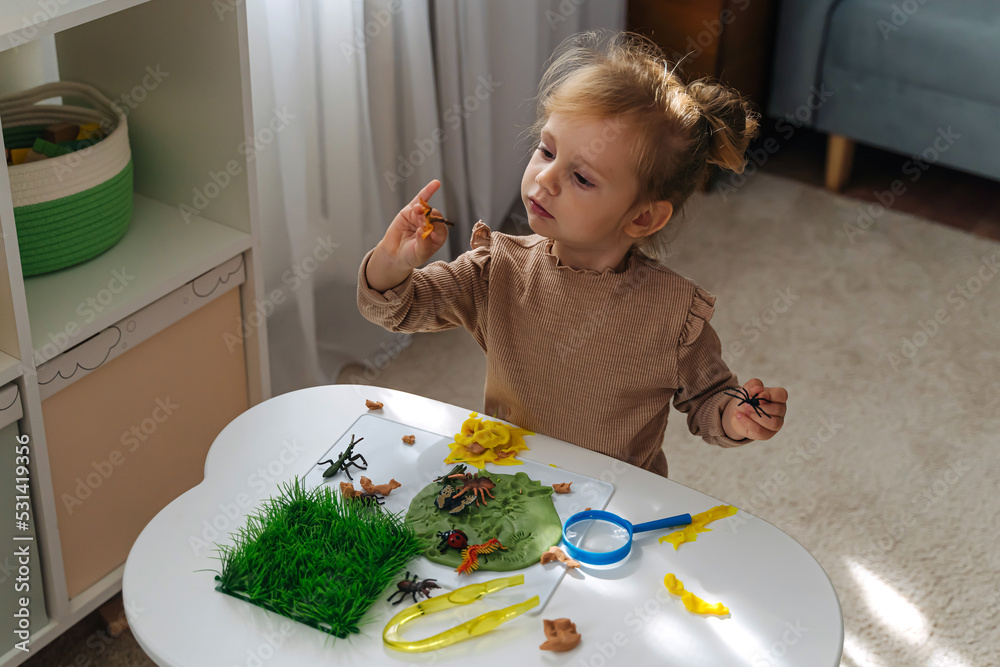 A little girl playing with toy insects. Educational game Bug Fossils ...
